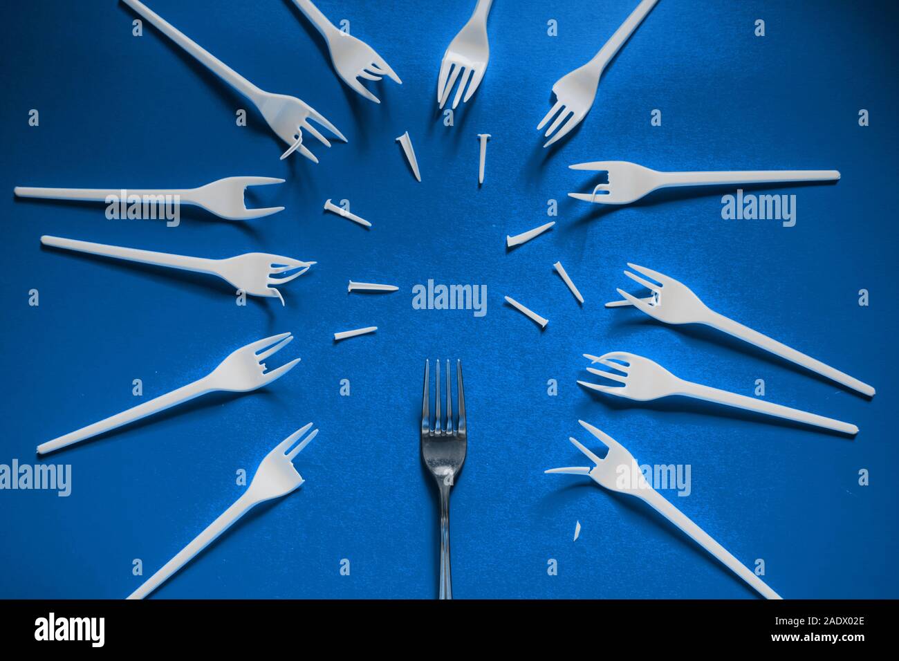 A plastic fork vs metal one on a blue background. The concept of ...