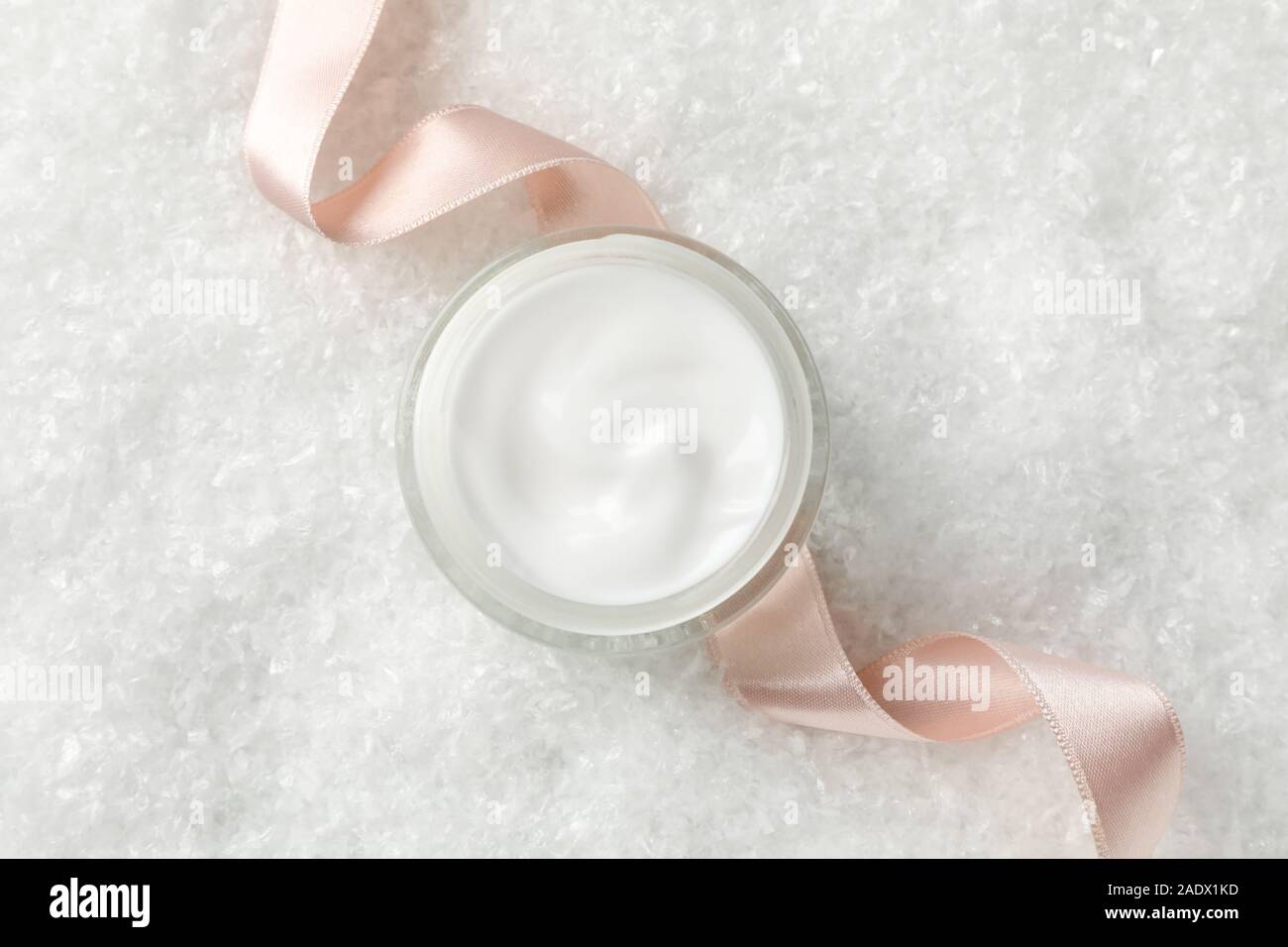 Jar of winter cream for skin on snowy background, space for text. Top ...