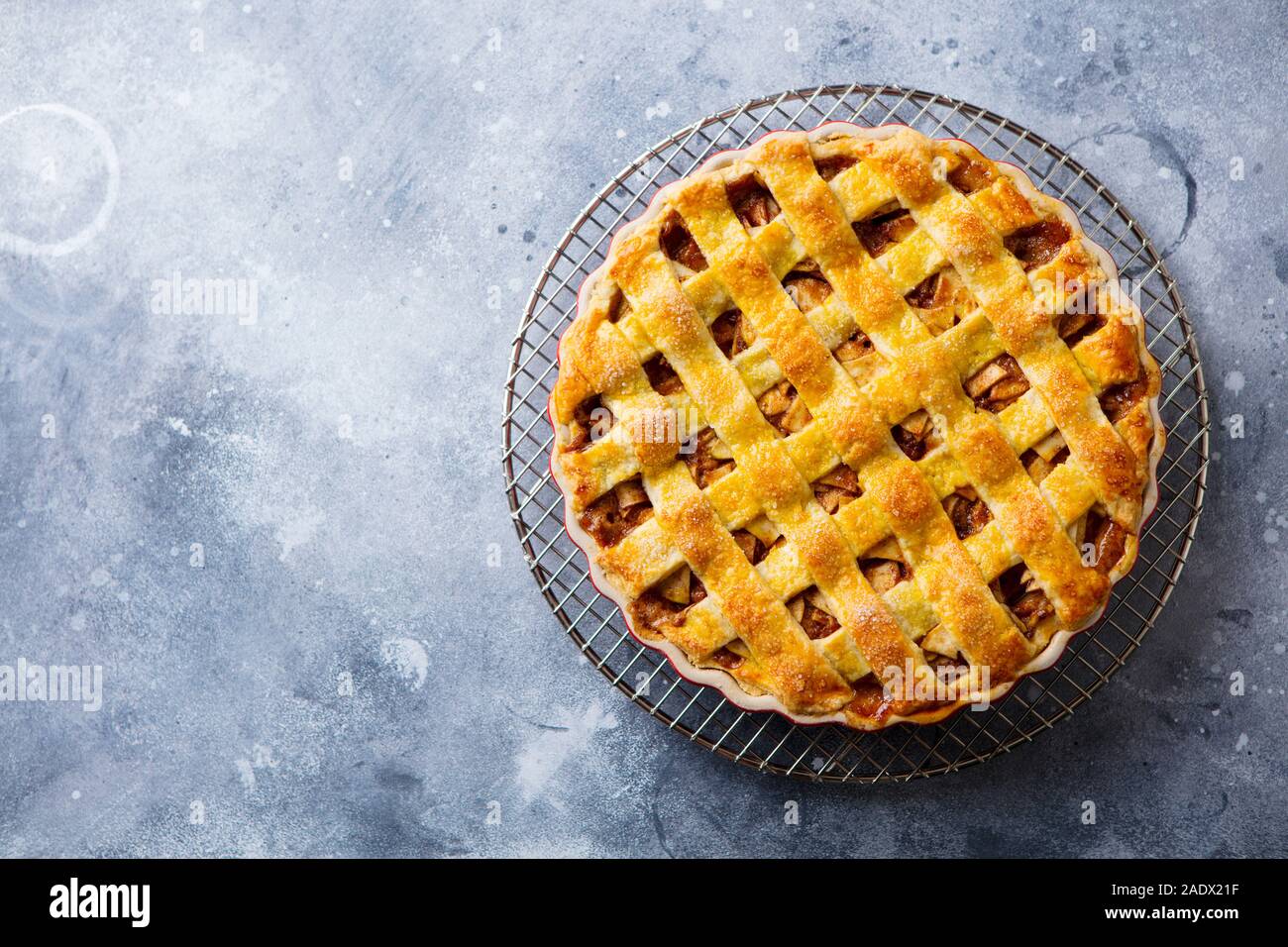 Apple pie with caramel on a cooling rack. Grey background. Copy space ...