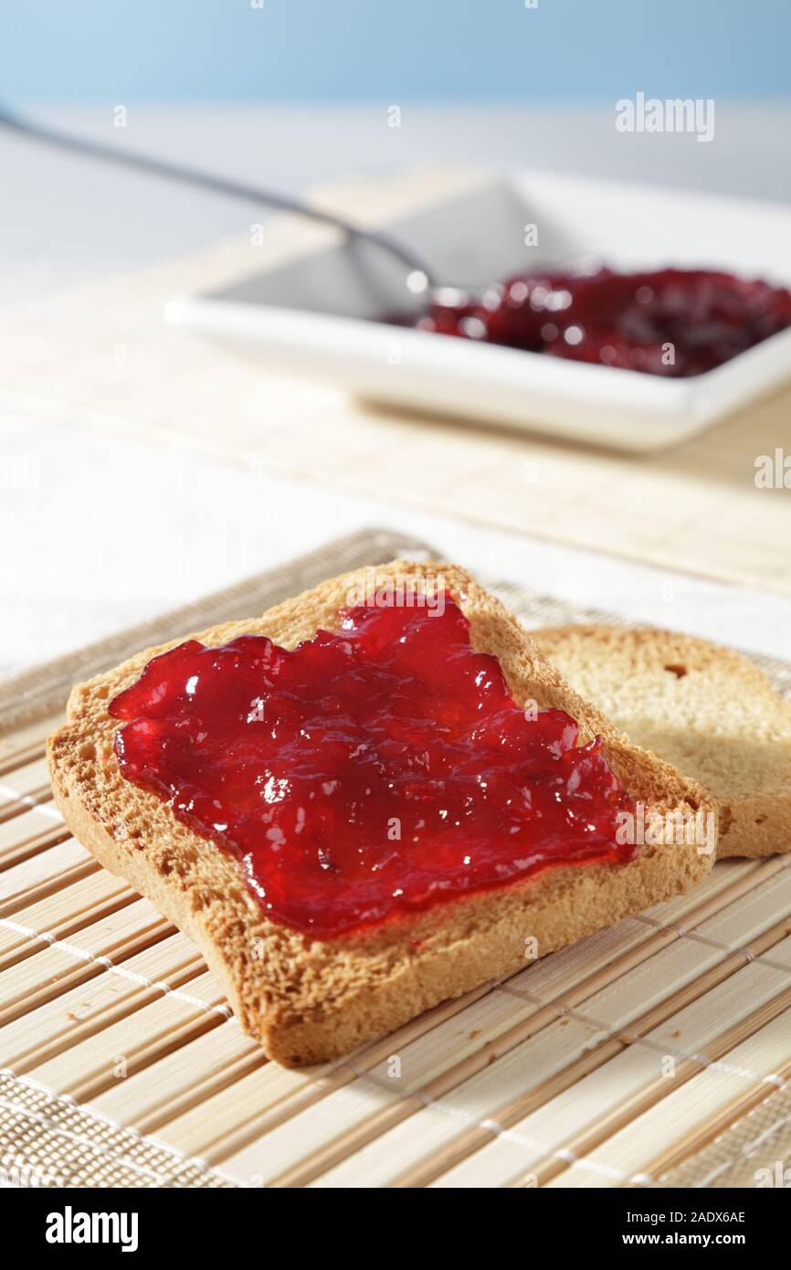 melba toast with red jam on table with pale blue background Stock Photo ...