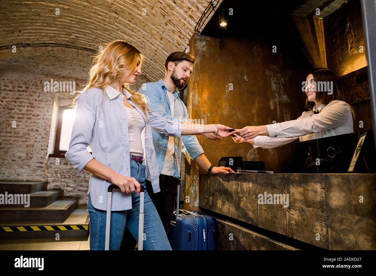 Happy young couple, man and woman, standing at stylish hotel reception ...