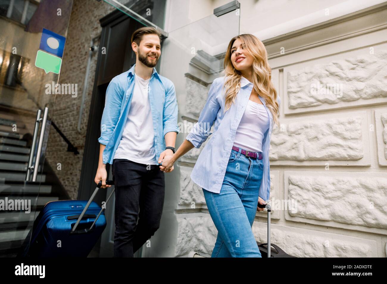 Happy young man and woman leaving hotel with luggage Stock Photo - Alamy