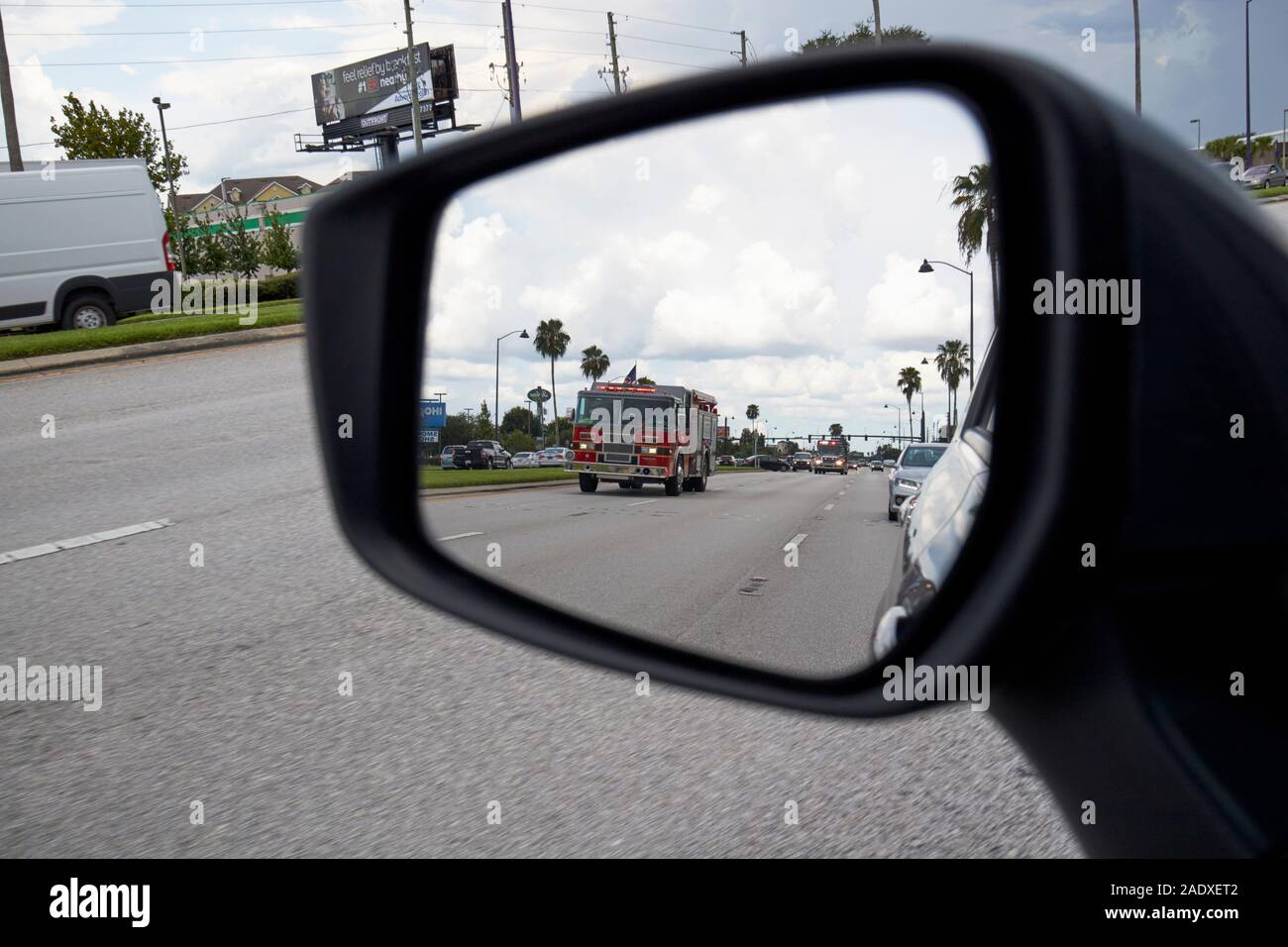 looking in side view rear mirror of approaching fire trucks on highway ...