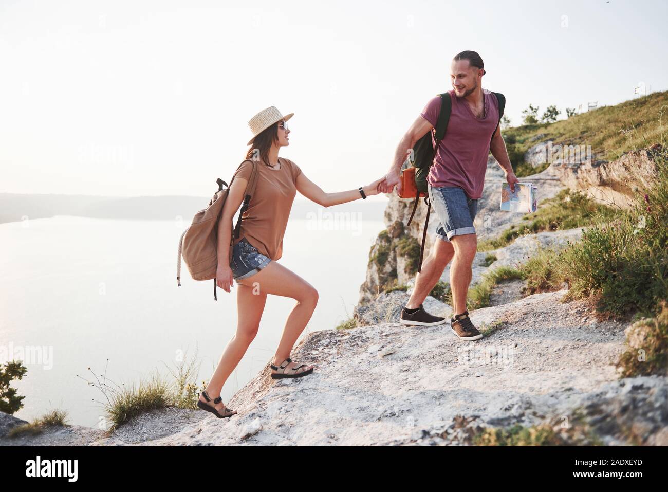 Two tourist with backpacks climb to the top of the mountain and ...