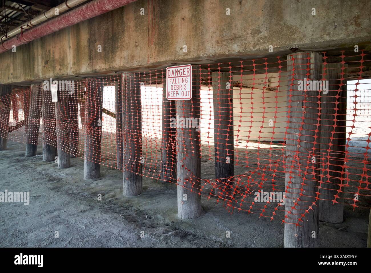 danger warning sign and orange barrier nets under the pier at daytona ...