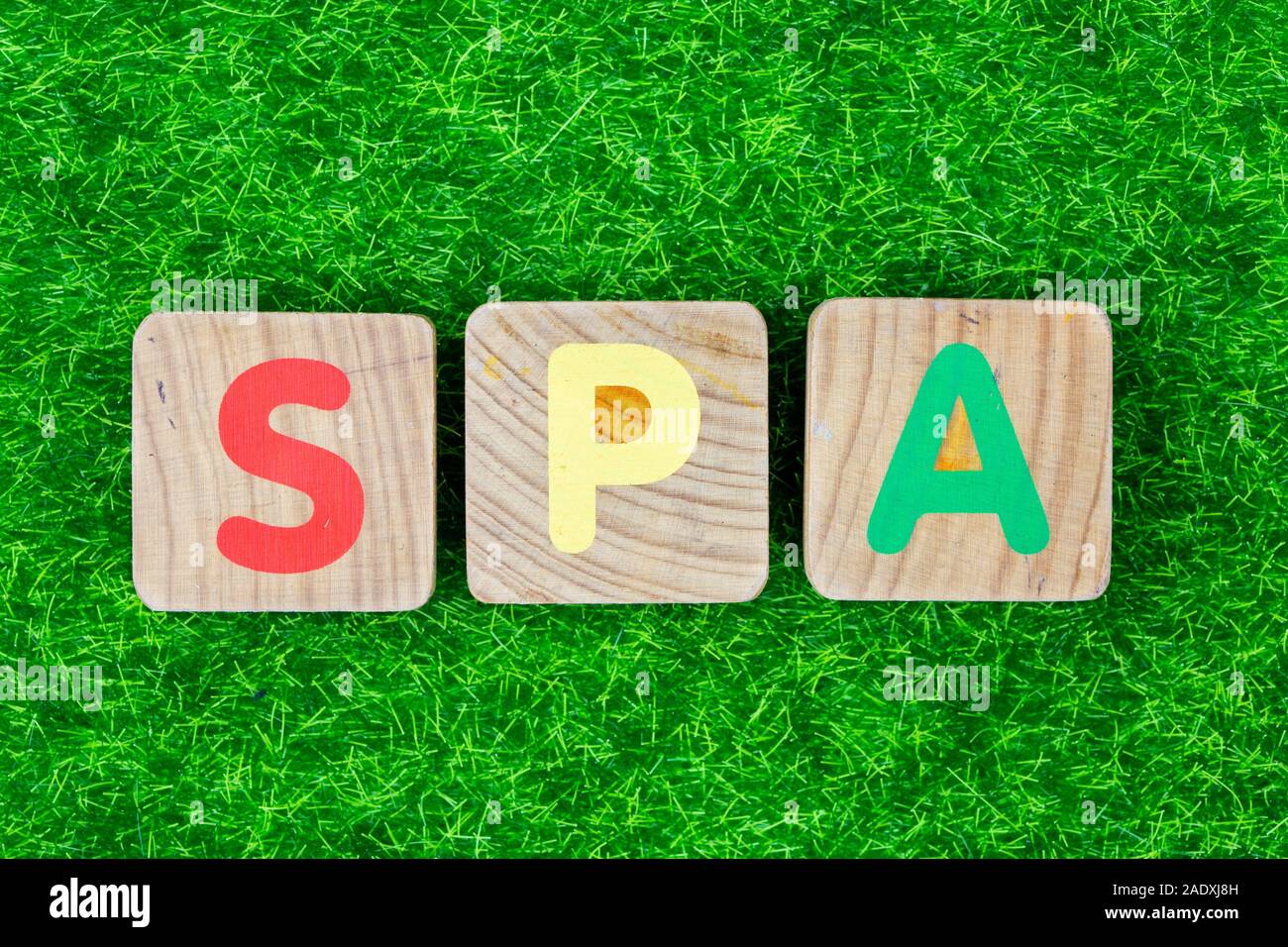 Word SPA written in wood letters laid on grass. Concept of wellness ...