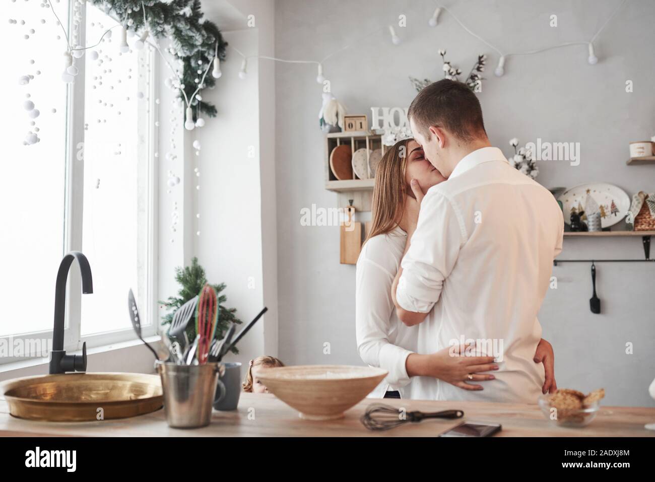Lovely people. Happy couple kissing in the kitchen. Having nice weekend ...