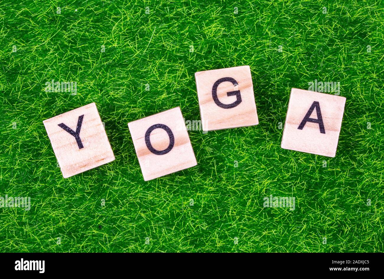 Word YOGA written in wooden letters laid on grass. Concept of wellness ...