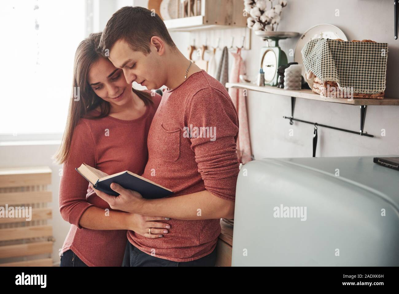 Cute couple reading book together at home in the kitchen at daytime ...