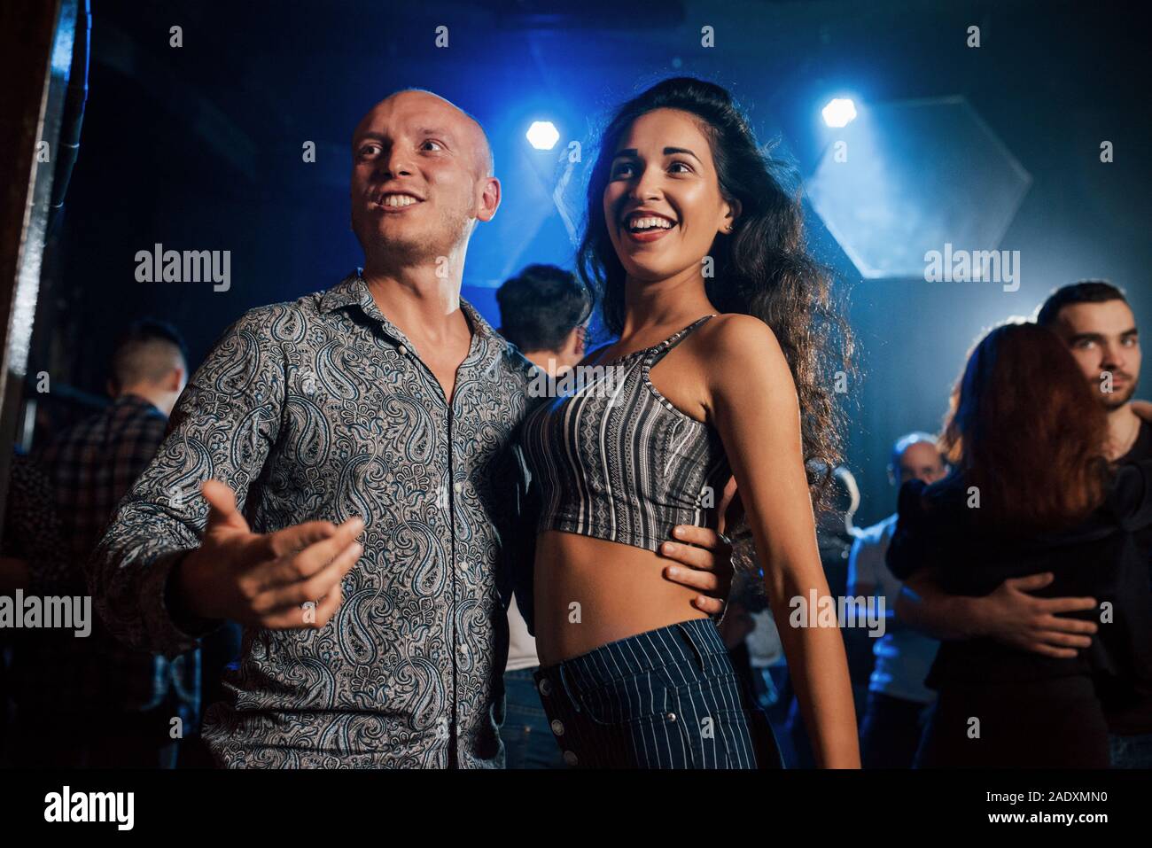 Couple having fun in the nightclub. Guy holds his girl by her waist ...
