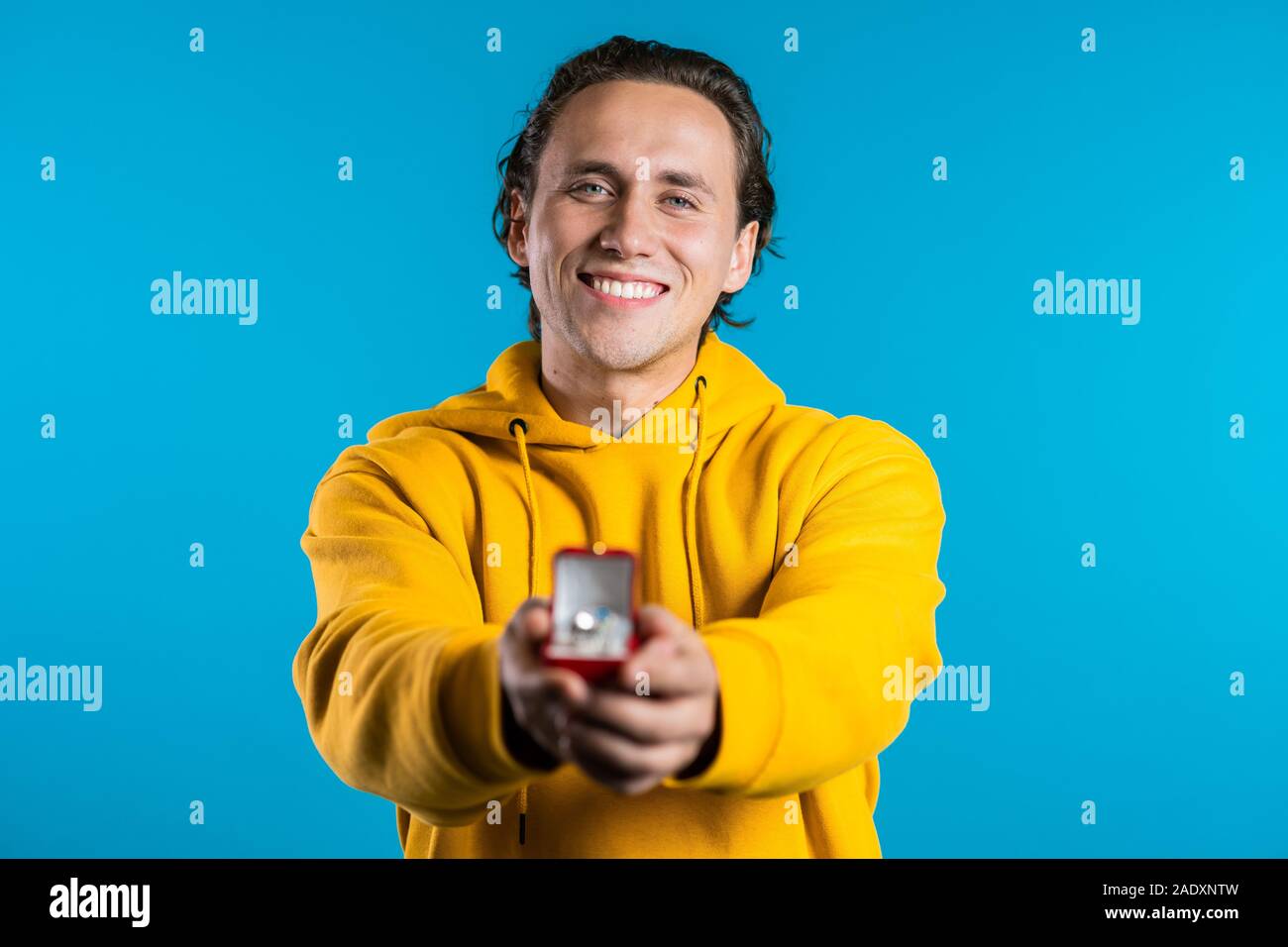 Young handsome guy holds out jewelry box with wedding ring to the ...