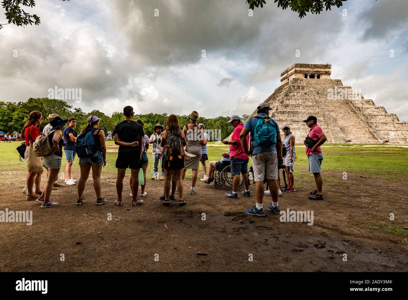 A group of tourists stand in front of Chichen Itza ancient Maya ...