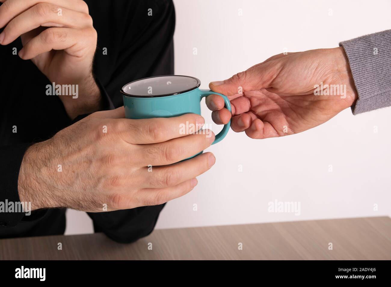 A woman's hand gives a cup of coffee to a man's hand Stock Photo - Alamy