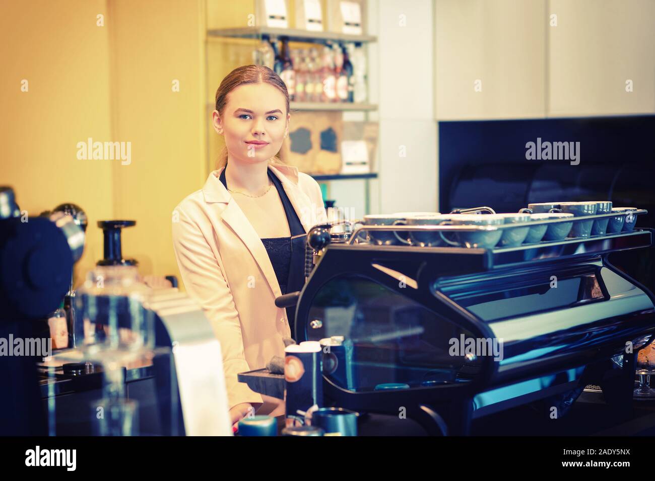 Portrait of smiling mid owner standing behind counter while looking at ...