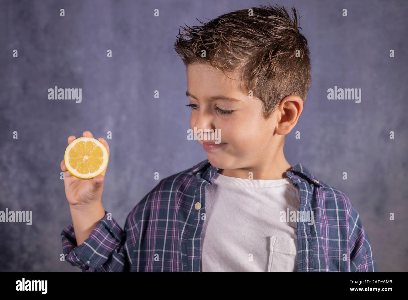 Cute child showing a lemon isolated in blue Stock Photo - Alamy
