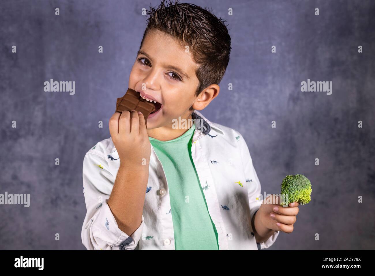Little kid choosing between broccoli and chocolate Stock Photo - Alamy