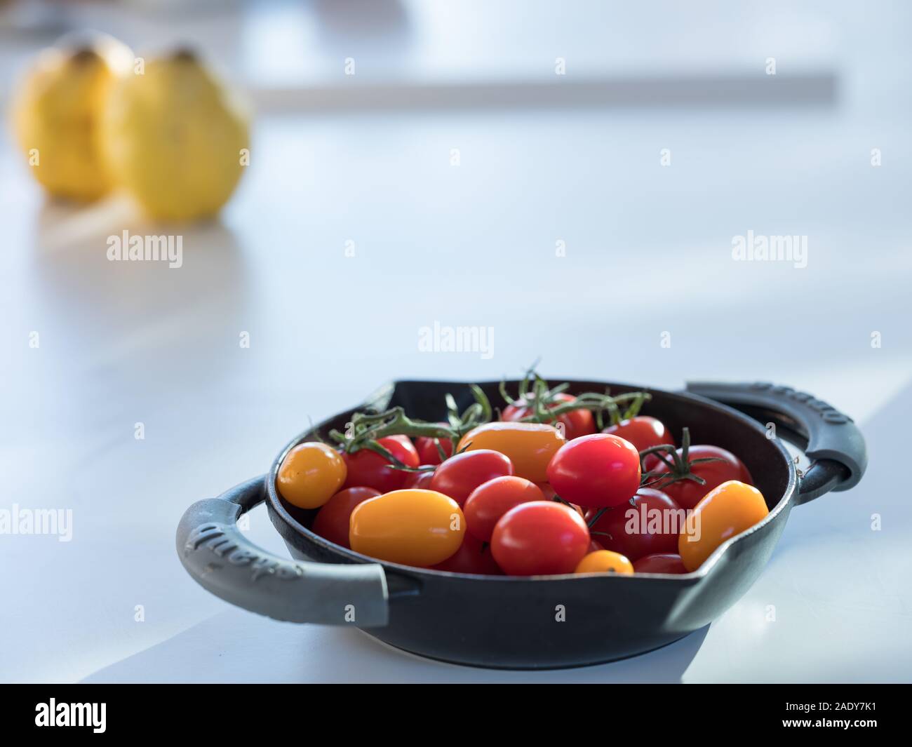 Red and yellow tomatoes in a rustic steel black bowl on the kitchen ...