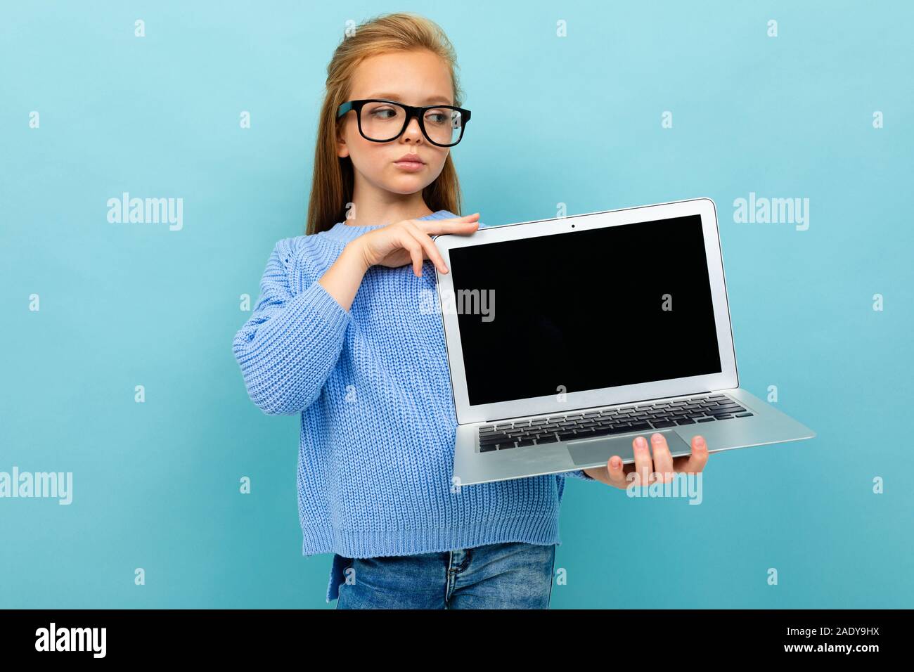 serious european girl holding a computer in her hands with the screen ...