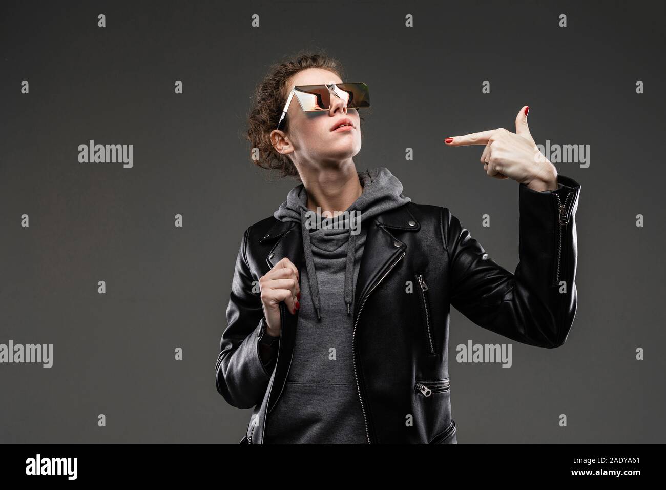 A young girl with rough facial features in a black jacket shows ...