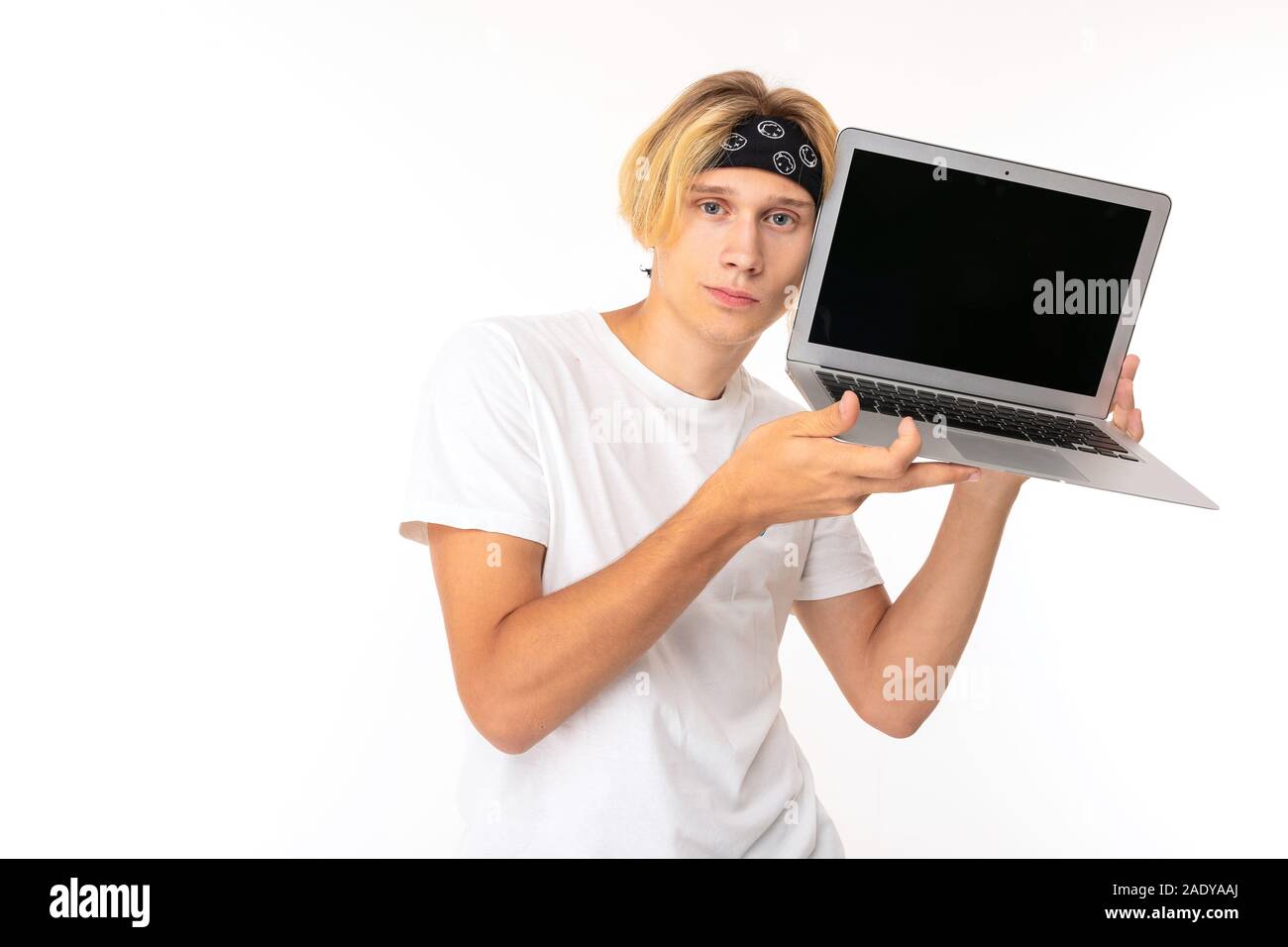 Stylish caucasian blonde man shows laptop isolated on white background ...