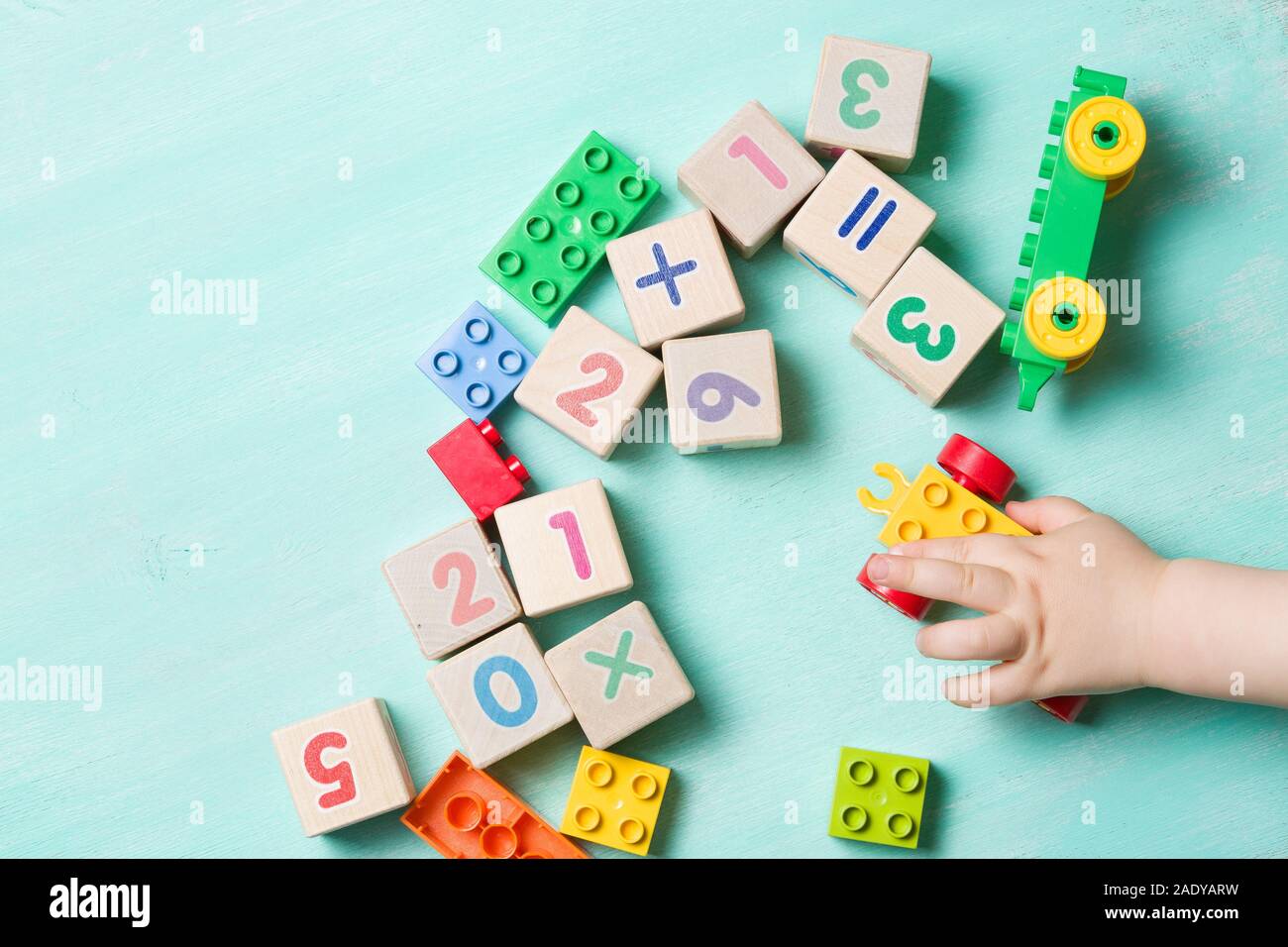 Child playing with wooden cubes with numbers and colorful toy bricks on ...