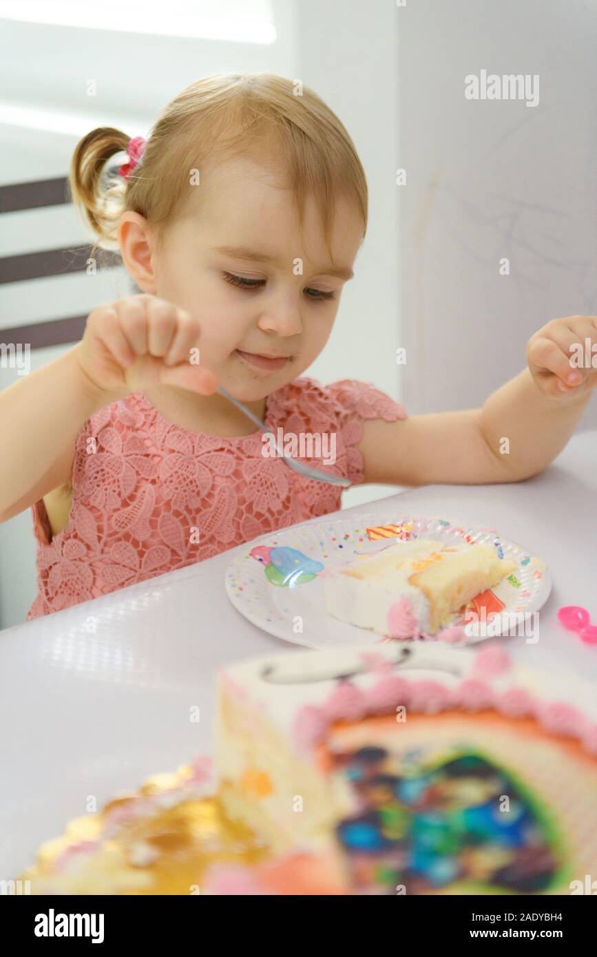 Baby girl 1 year old eating birthday cake in room. Birthday party ...