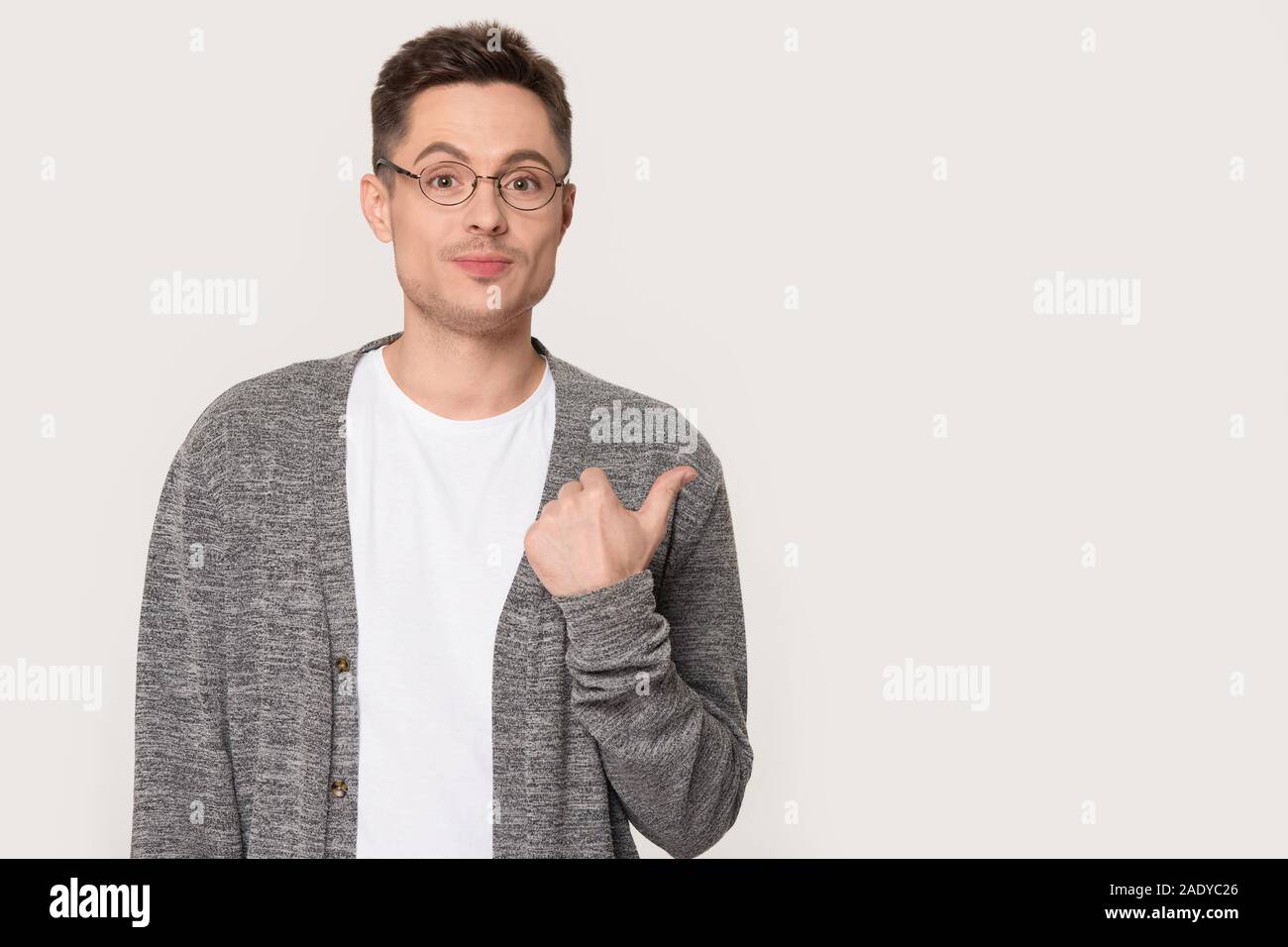 Millennial man pointing big finger to left isolated on gray Stock Photo ...