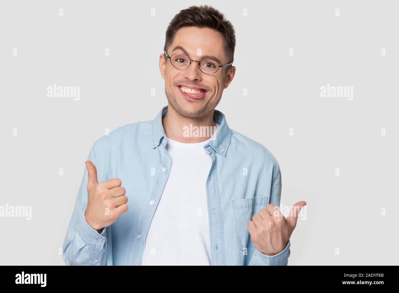 Young man with funny nerd jerk face showing thumb up Stock Photo - Alamy