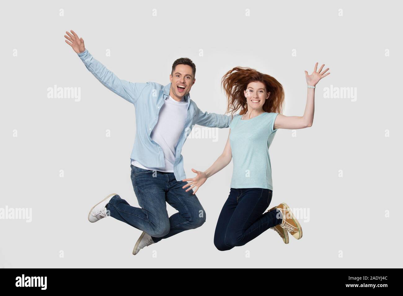 Energetic friends jumping high together on grey studio background Stock ...