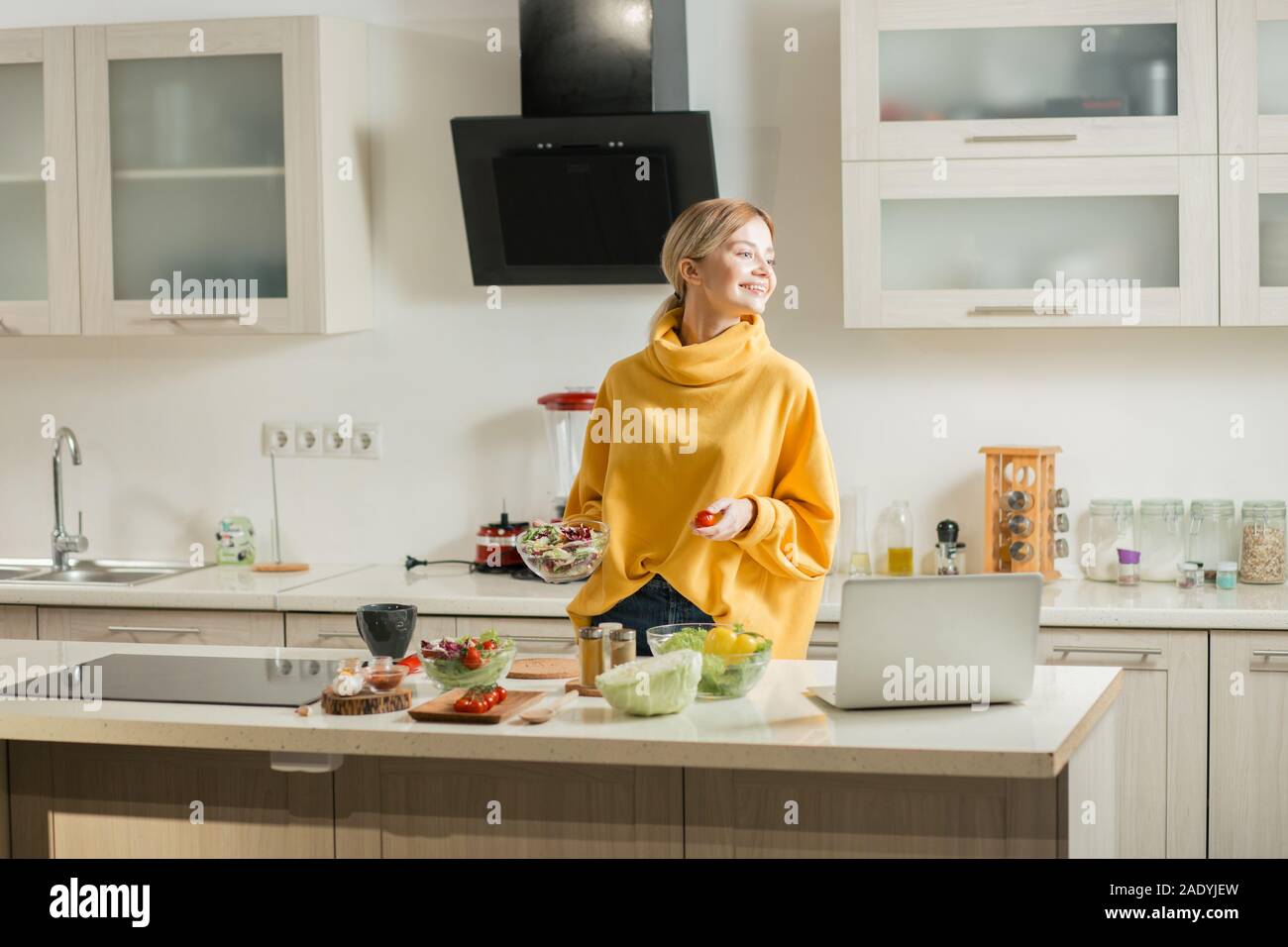 Happy lady cooking in the kitchen and smiling while looking away Stock ...