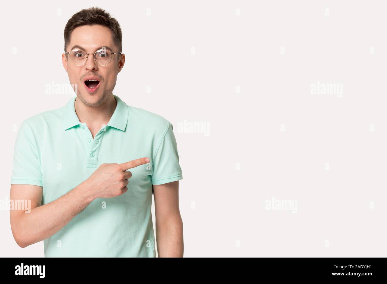 Surprised young man pointing at copy space for advertisement text Stock ...