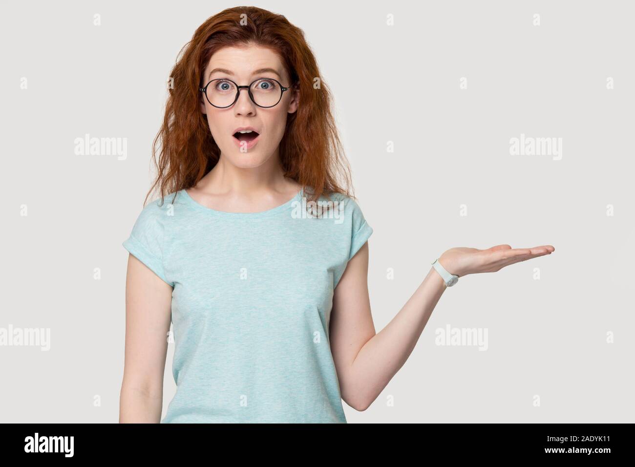 Surprised millennial red-haired woman demonstrating free copy space ...
