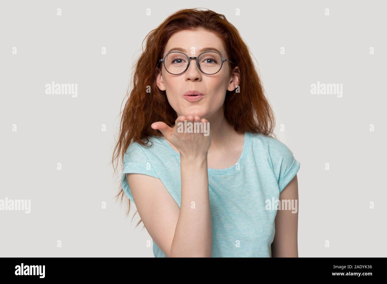 Millennial red-haired woman in eyeglasses sending air kisses Stock ...