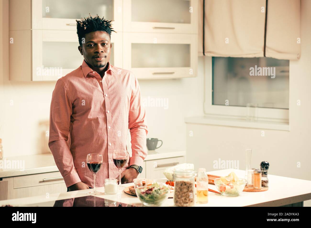 Calm man standing in the kitchen and looking at the camera Stock Photo ...