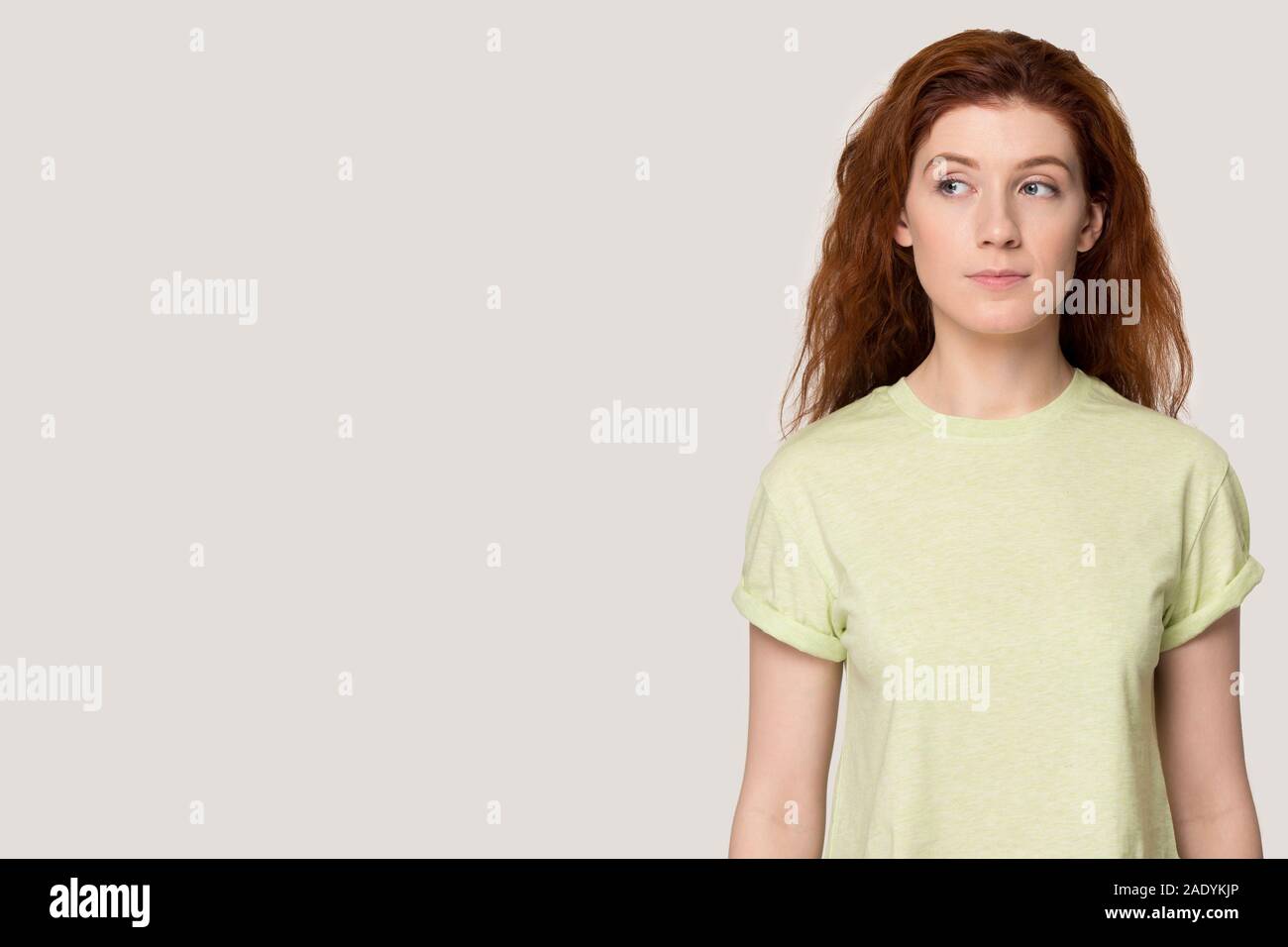 Concentrated millennial red-haired woman standing aside Stock Photo - Alamy
