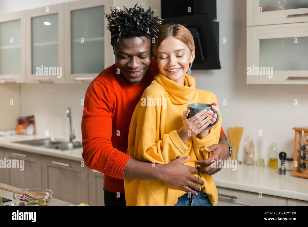 Happy lady drinking tea and boyfriend hugging her Stock Photo - Alamy