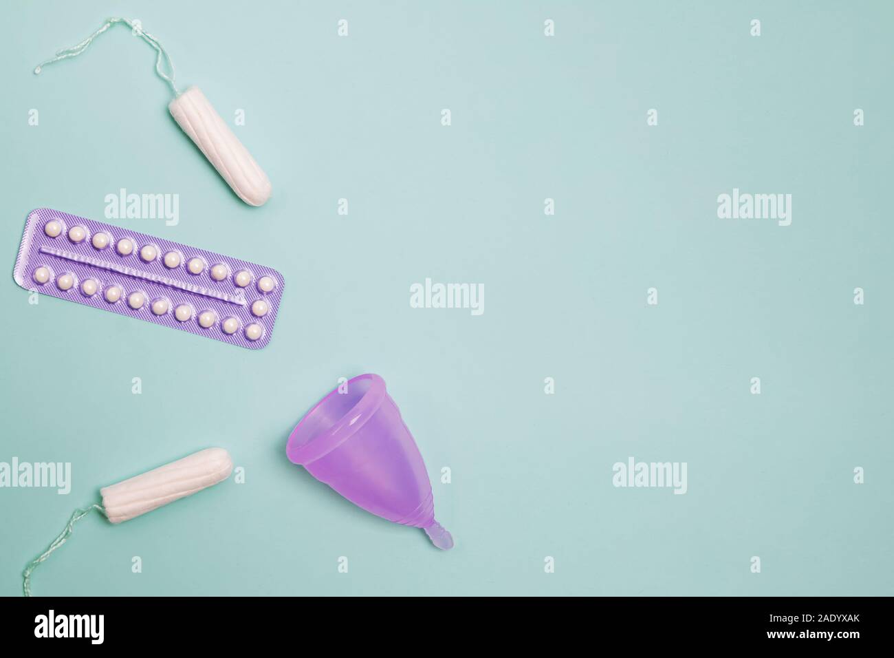 Menstrual cup, tampons and oral contraceptive tablets on pastel ...