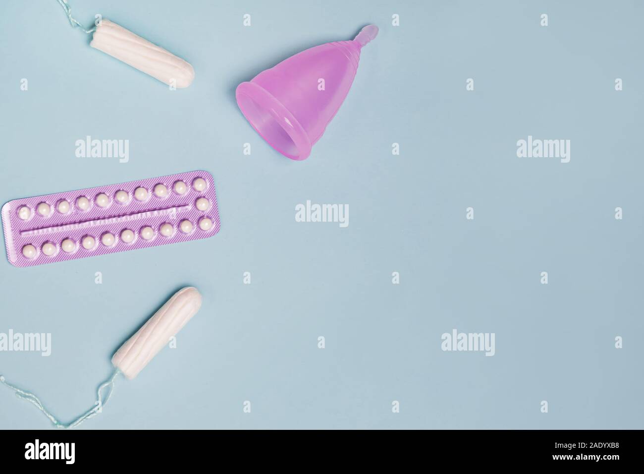 Tampons, menstrual cup and blister of oral contraceptives on pastel ...