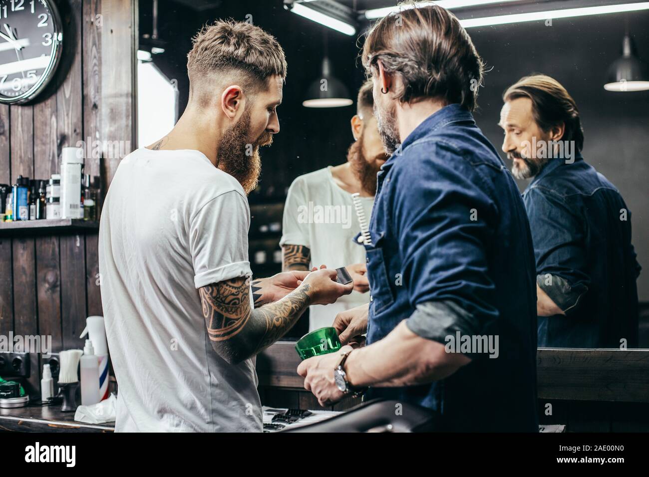 Curious man standing next to professional barber and looking at blades ...