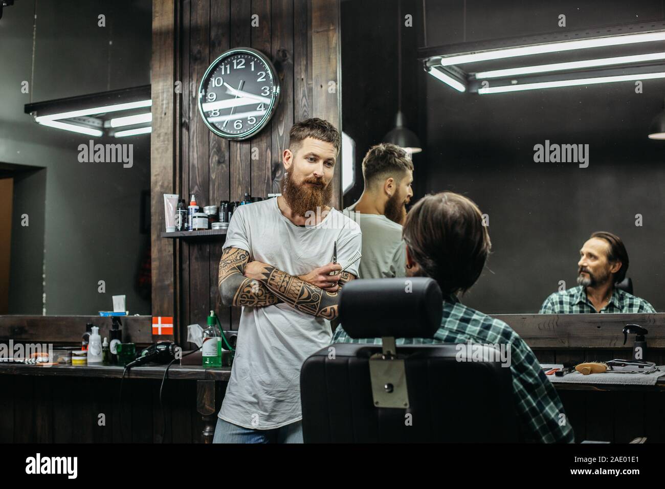 Curious barber looking at his client and talking to him Stock Photo - Alamy