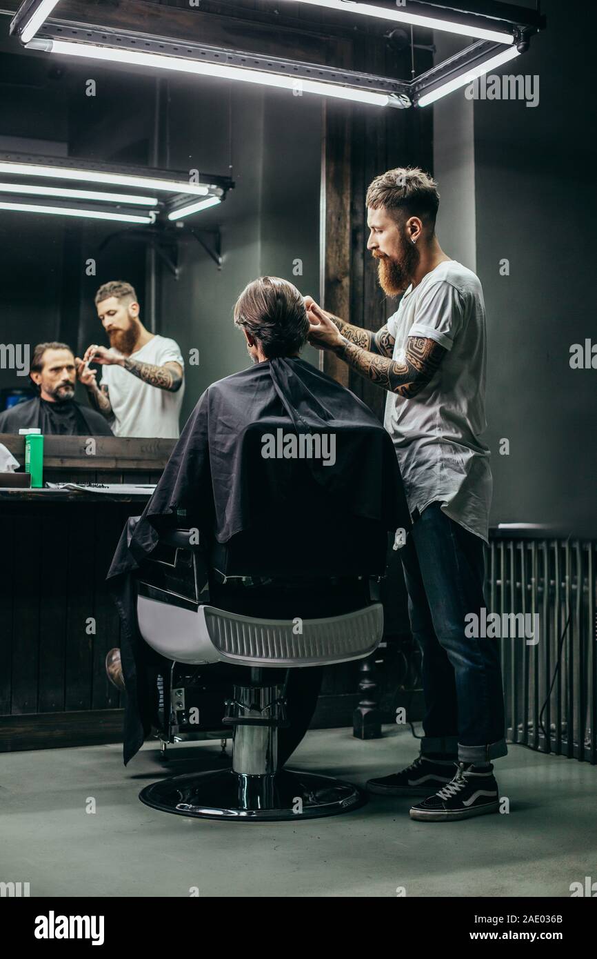 Full length of barber doing haircut for his visitor Stock Photo - Alamy