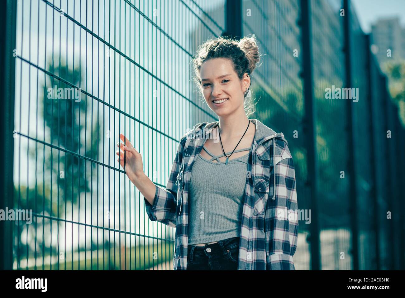 Pretty lady smiling and touching the chain link fence Stock Photo - Alamy