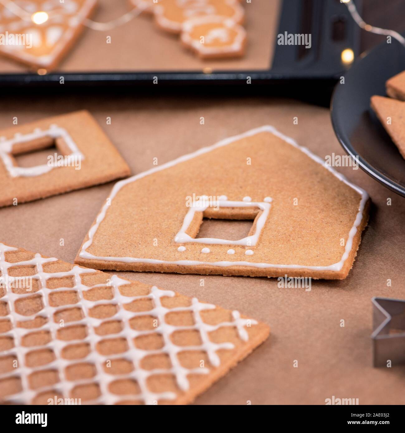 Woman is decorating gingerbread cookies house with white frosting icing ...