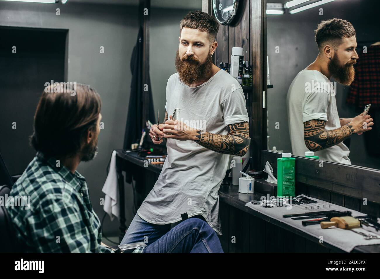 Calm barber looking at his client before doing the haircut Stock Photo ...