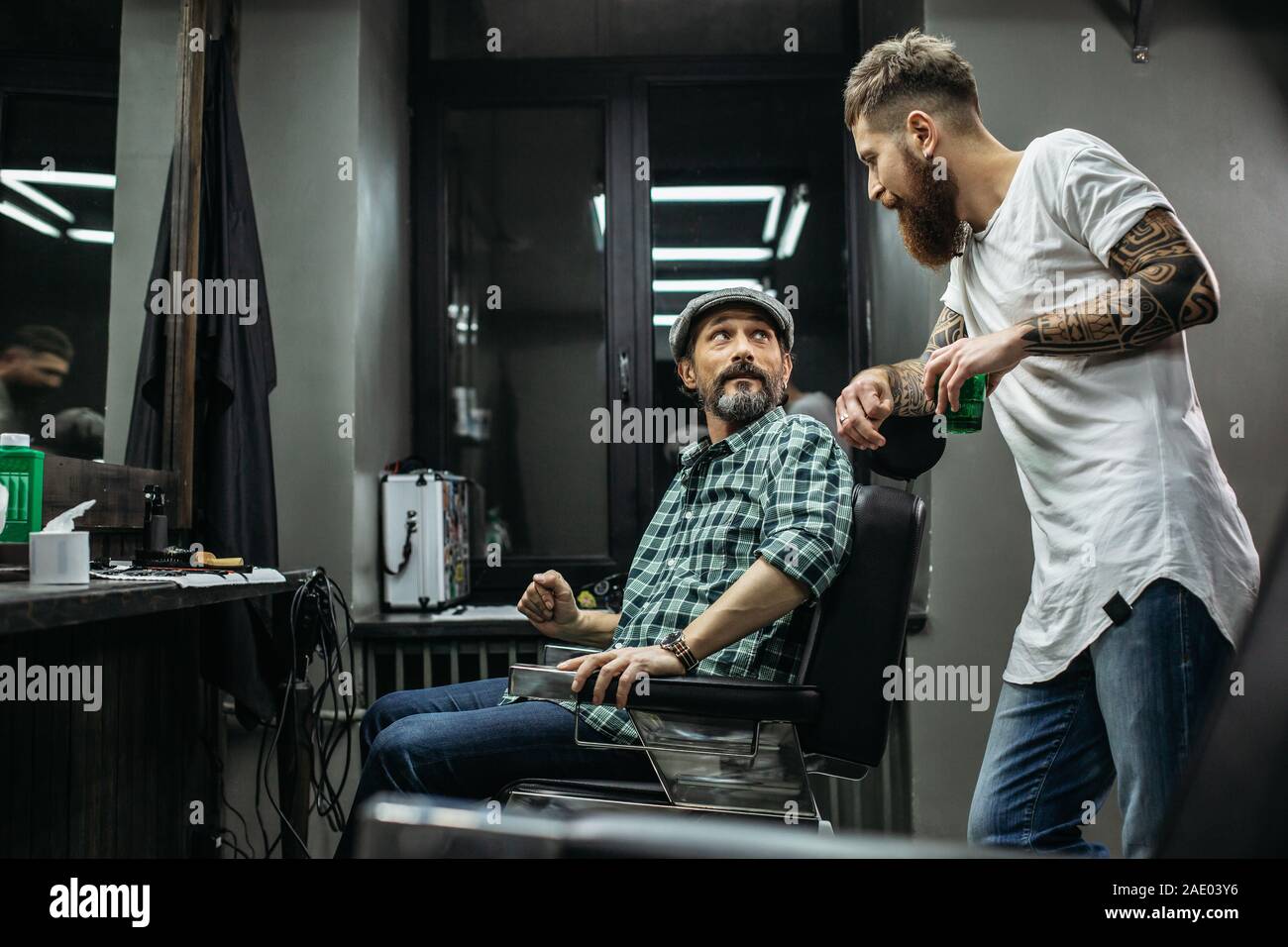 Bearded barber looking at his client while talking to him Stock Photo ...