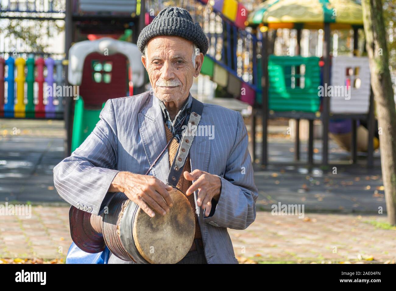 Portrait of an old man playing the tombak at park, Persian music ...
