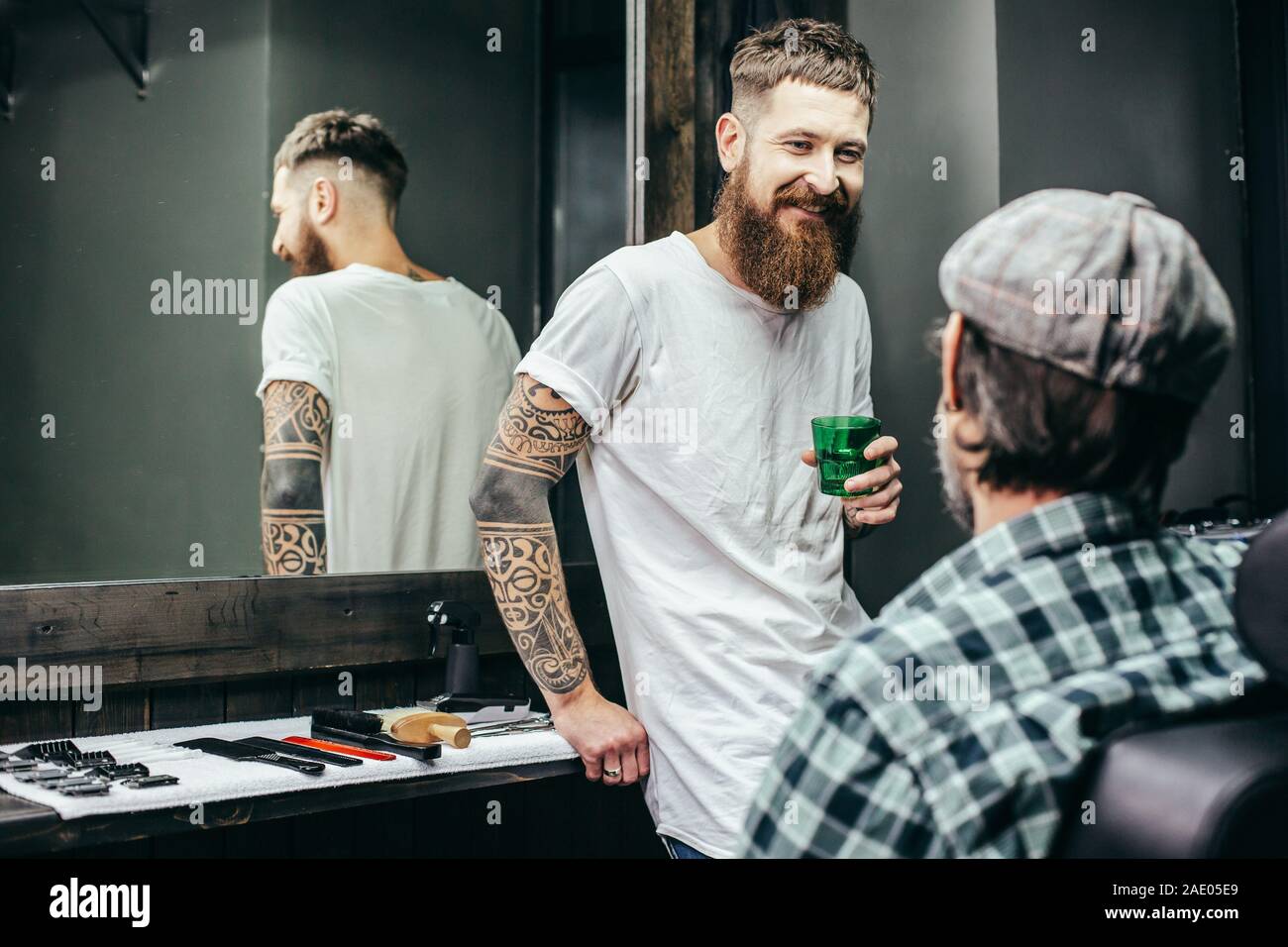 Waist up of positive barber smiling to his client in barbershop Stock ...