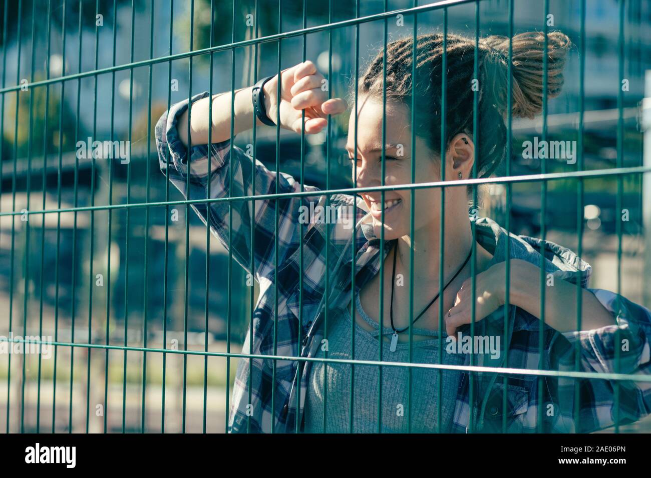 Positive lady smiling and looking through the chain link fence Stock ...