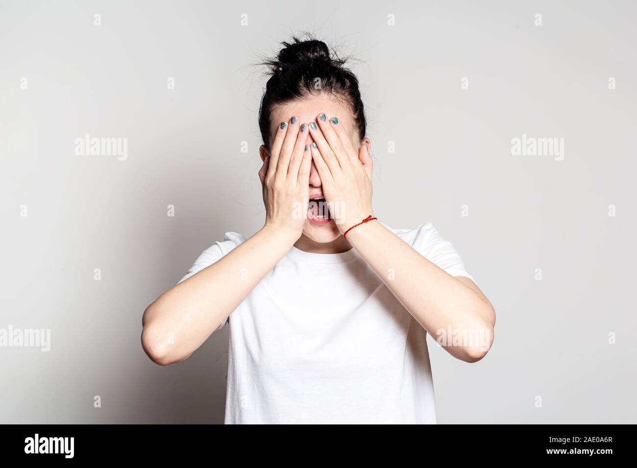 Sleepy, tired young woman covered her face with her hands and yawns ...