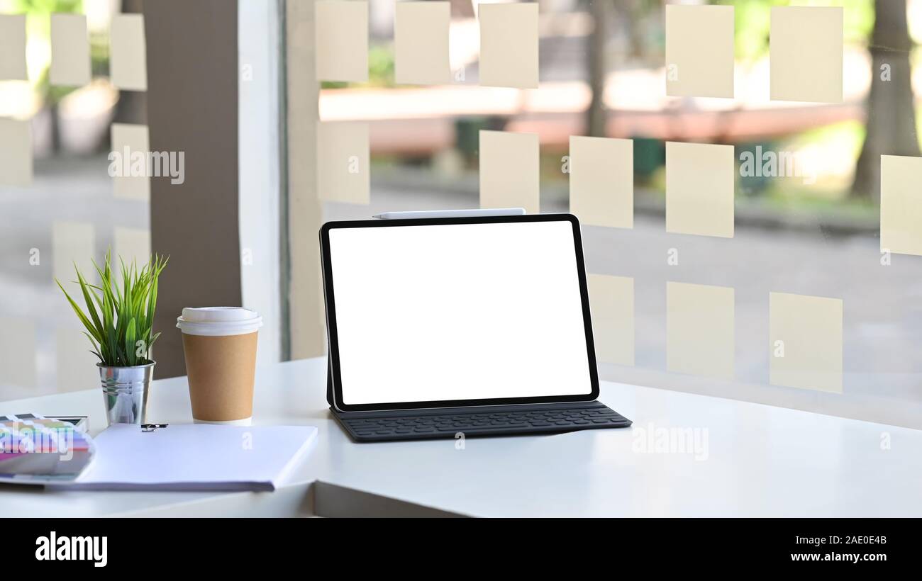 Tablet empty screen, coffee, plant and colour guide on white table with ...